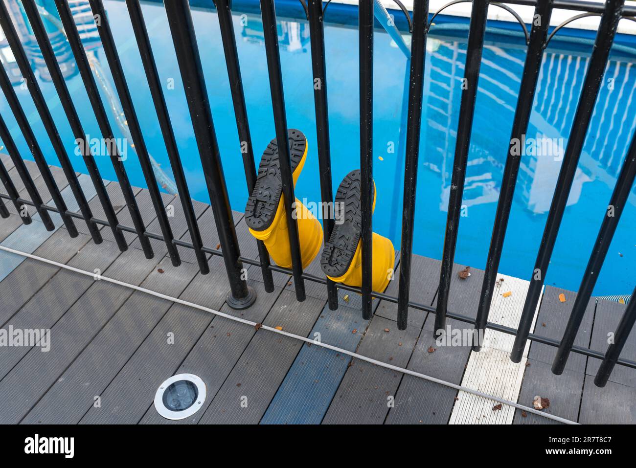 Yellow rubber boots headlong between the railing at the Gombak river in ...