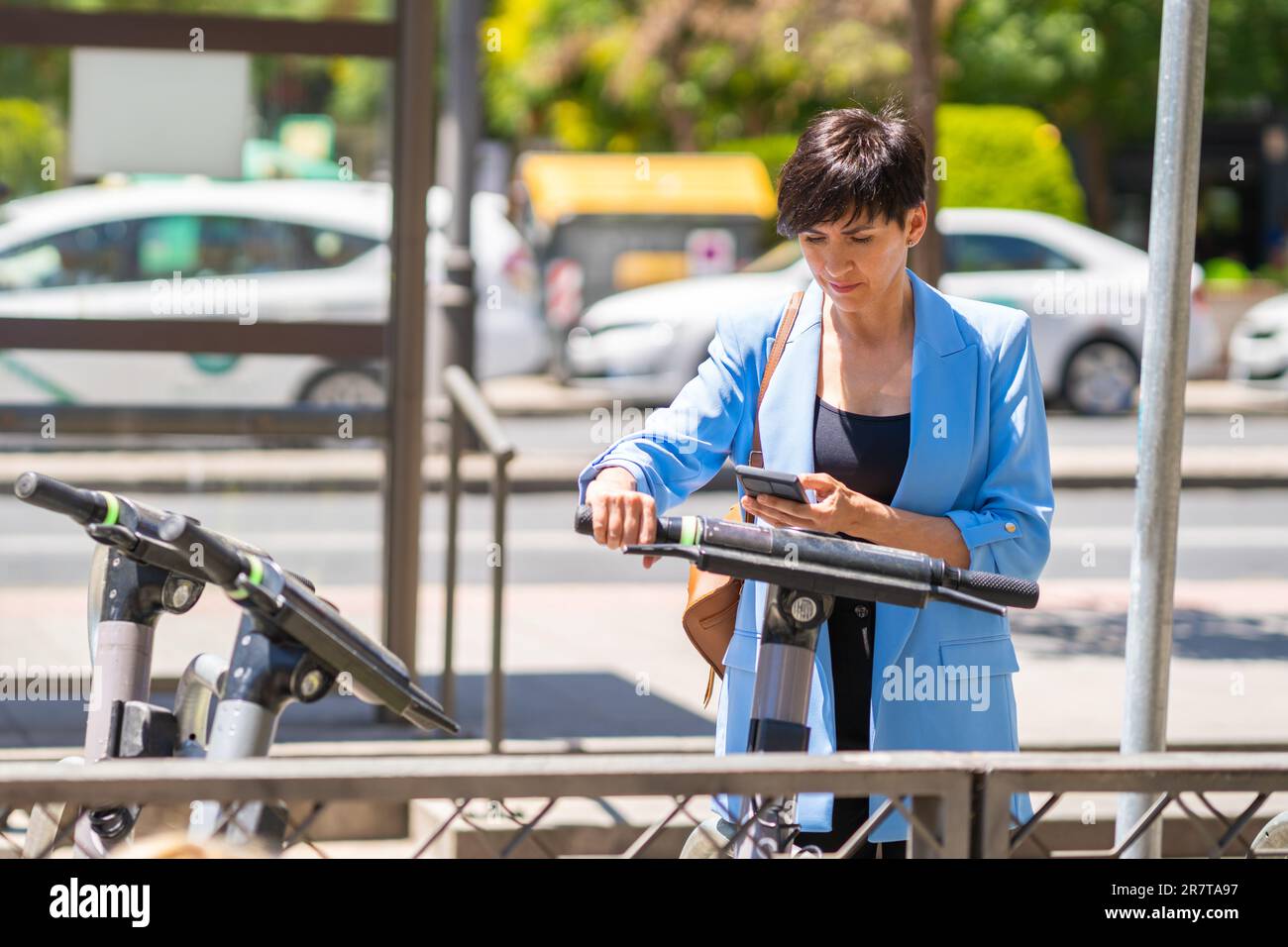 Serious woman scanning QR code on electric scooter Stock Photo - Alamy