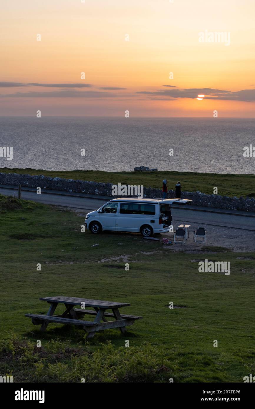 Campers with VW T6.1 Bulli camper watching the sunset at a picnic site ...