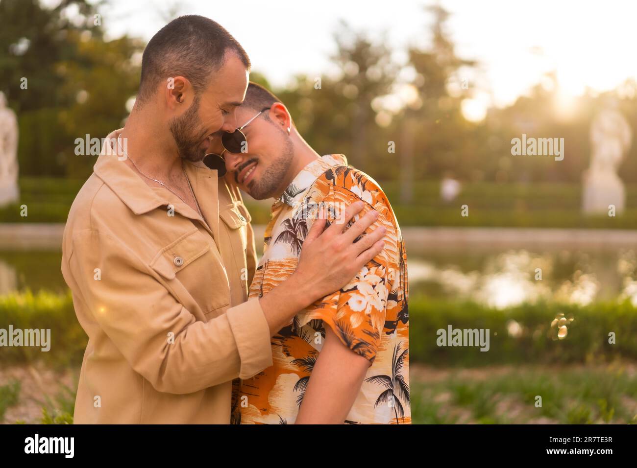 Homosexual couple embracing smiling at sunset in a park in the city ...