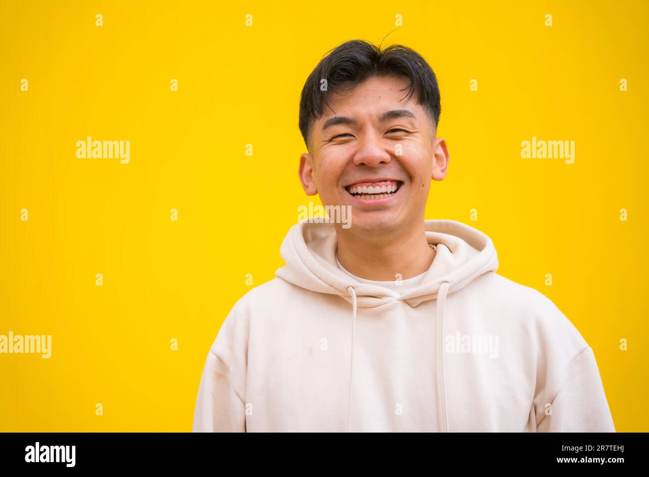 Portrait of a handsome Asian man in basic clothes smiling isolated over ...