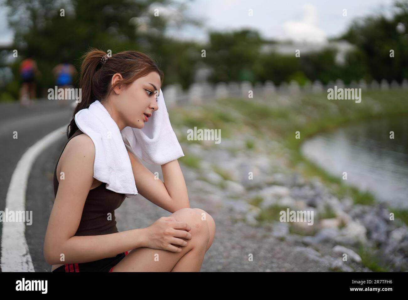 Young woman wiping sweat on face and neck during exercise in the city ...