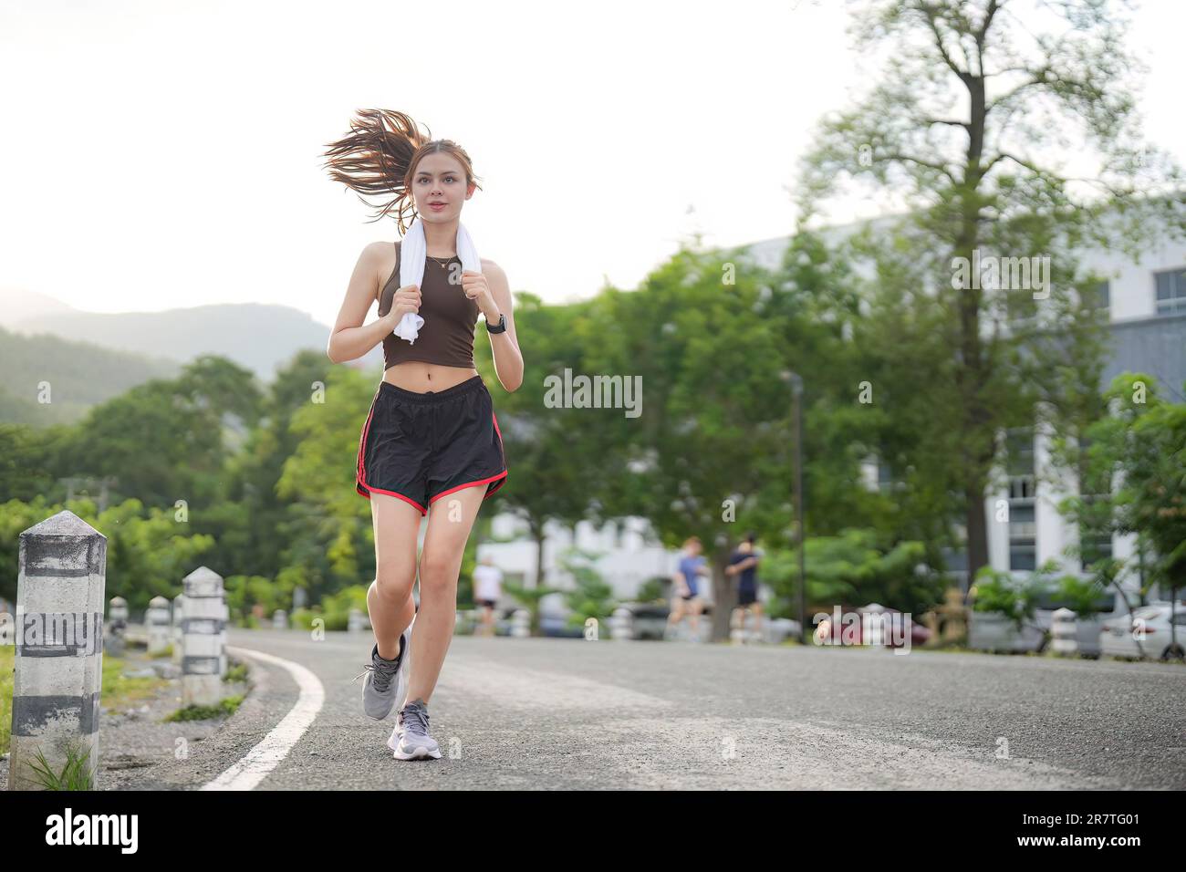 Young attractive beautiful athletic runner woman runs in the green park ...