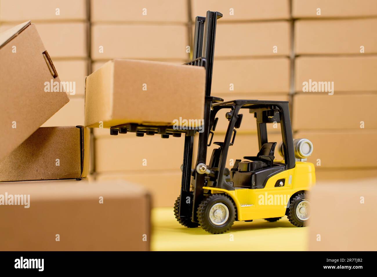 Forklift truck raises cardboard boxes on a yellow background. Cargo ...