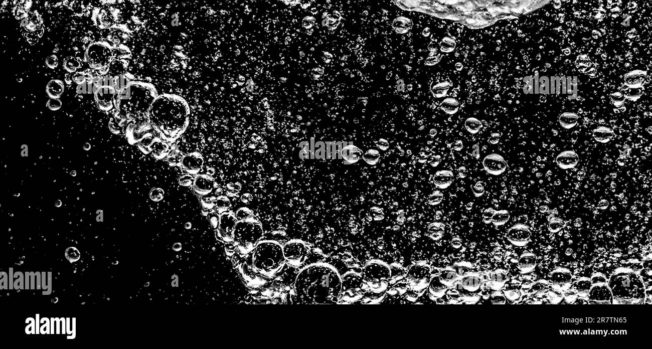 Soda water bubbles splashing underwater against black background. Cola liquid texture that ...