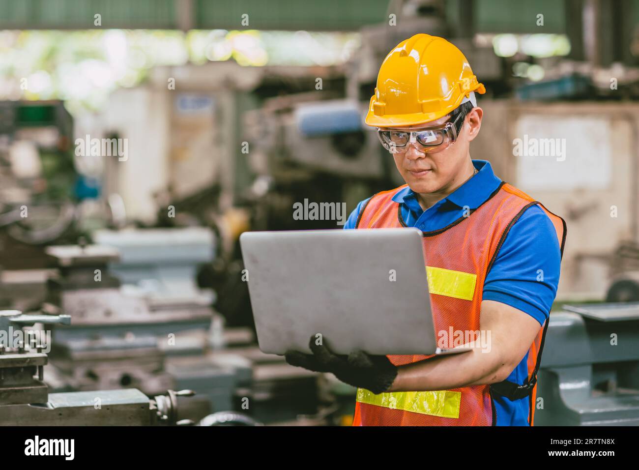 Asian male engineer worker happy using Laptop computer in heavy metal ...