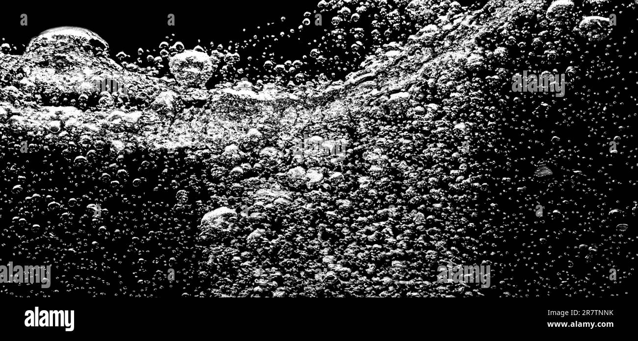 Soda water bubbles splashing underwater against black background. Cola liquid texture that ...