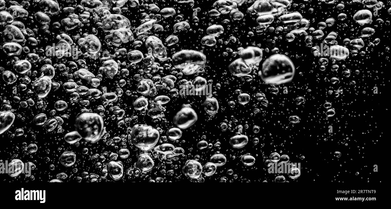 Soda water bubbles splashing underwater against black background. Cola liquid texture that ...