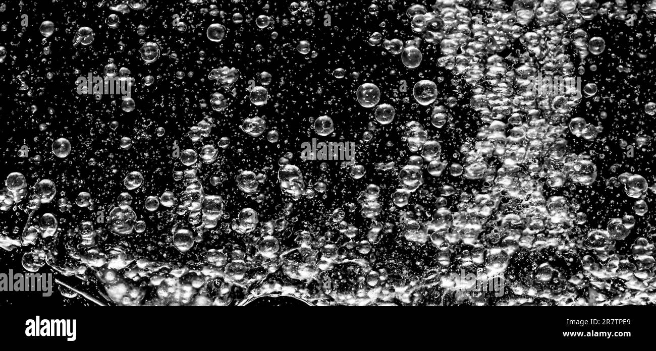 Soda water bubbles splashing underwater against black background. Cola liquid texture that ...
