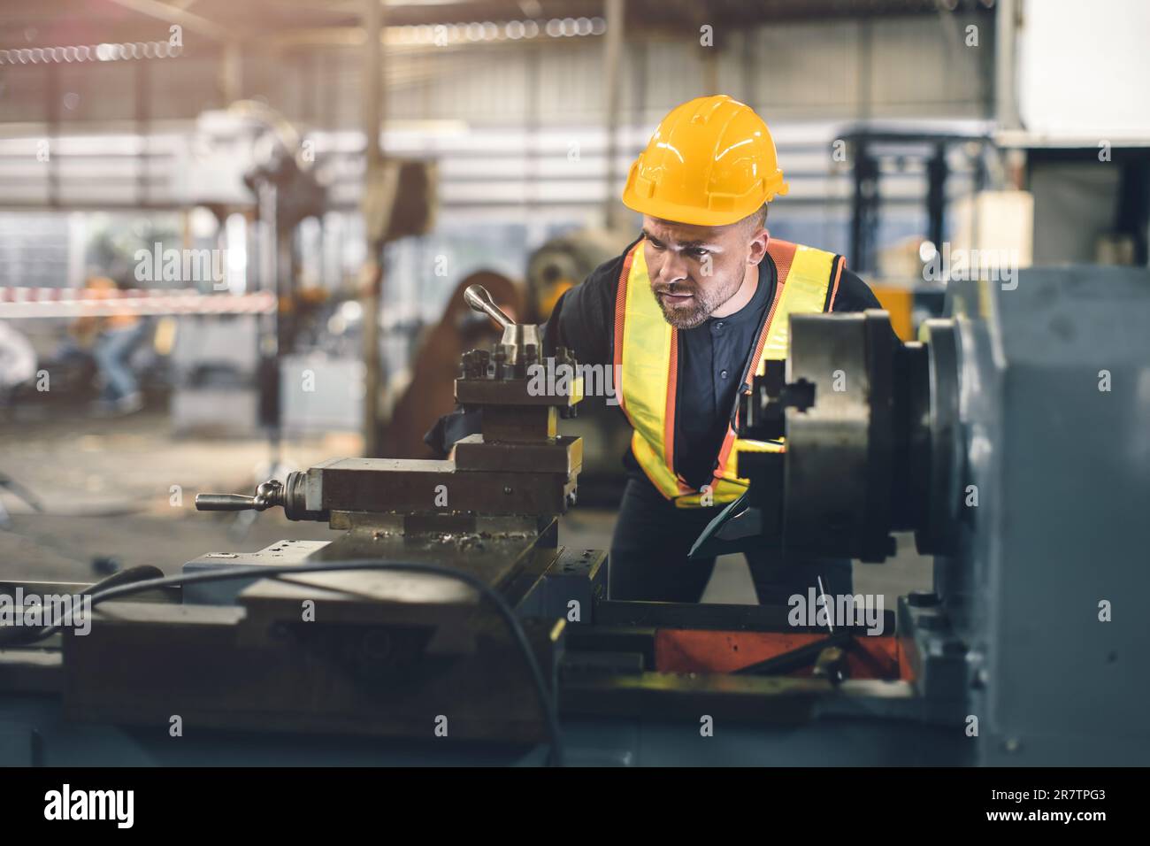 young engineer male worker work in heavy metal industry CNC lathe ...