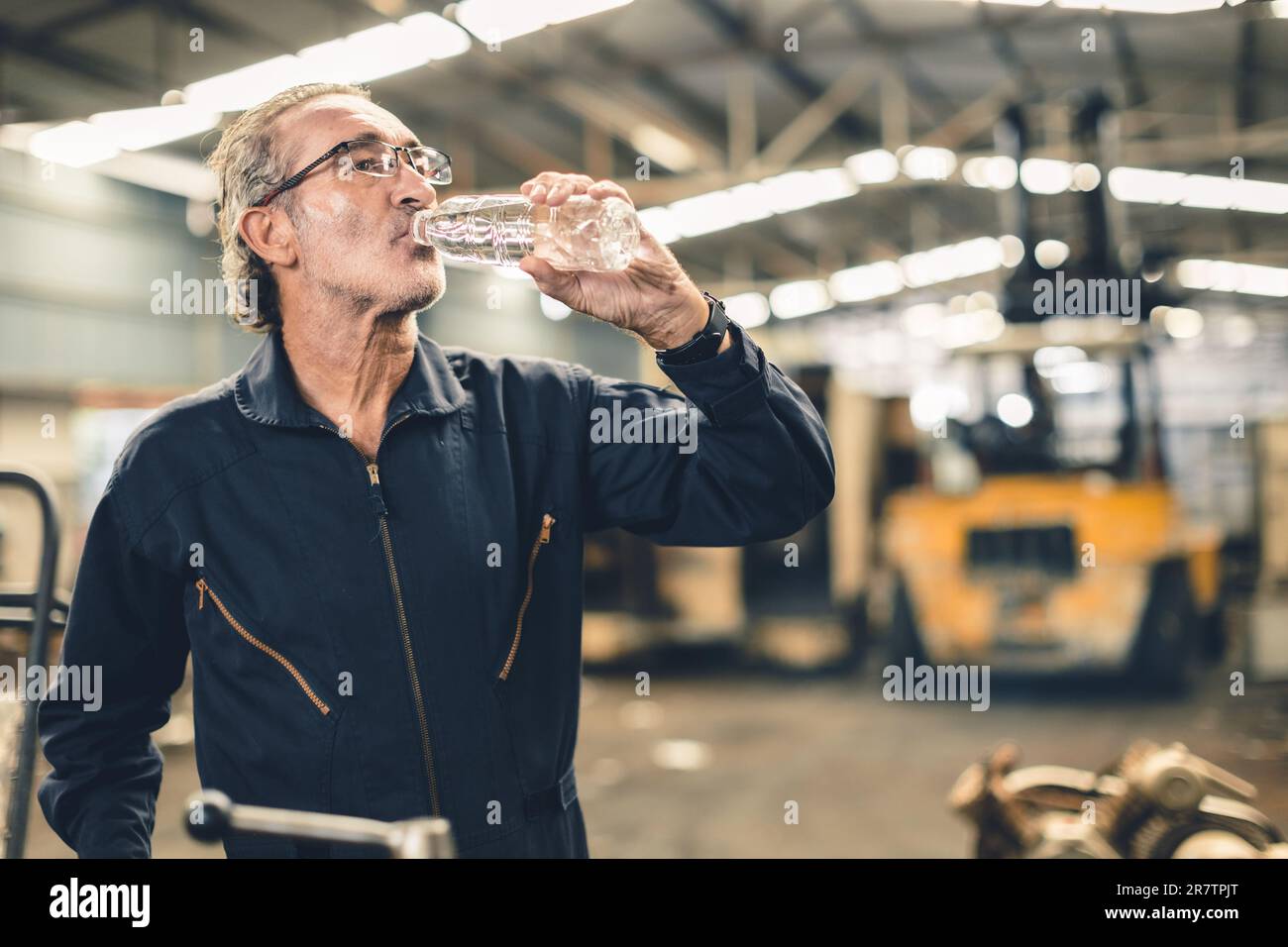Thirsty senior male staff worker drinking water refreshing from tired hard work in hot workplace ...