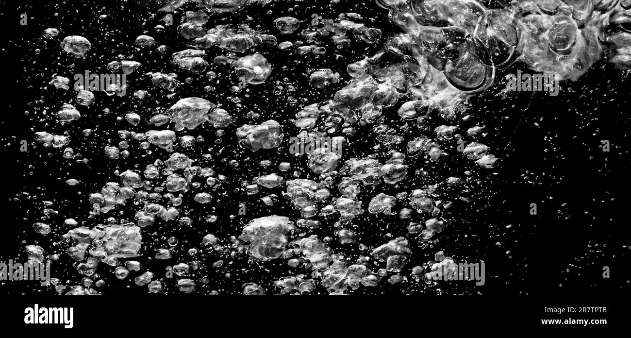 Soda water bubbles splashing underwater against black background. Cola liquid texture that ...