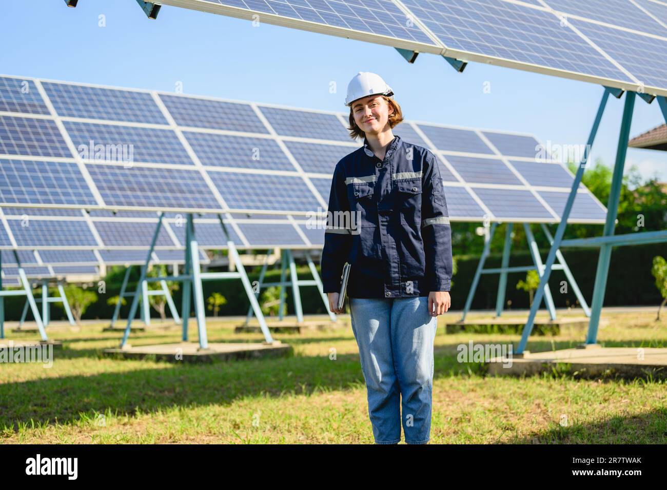 Female engineer holding laptop checking solar panels at solar farm ...