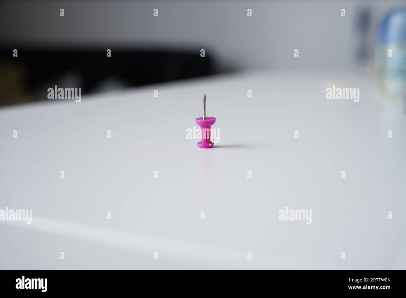 One pink pin stands alone on a white background table with space for ...