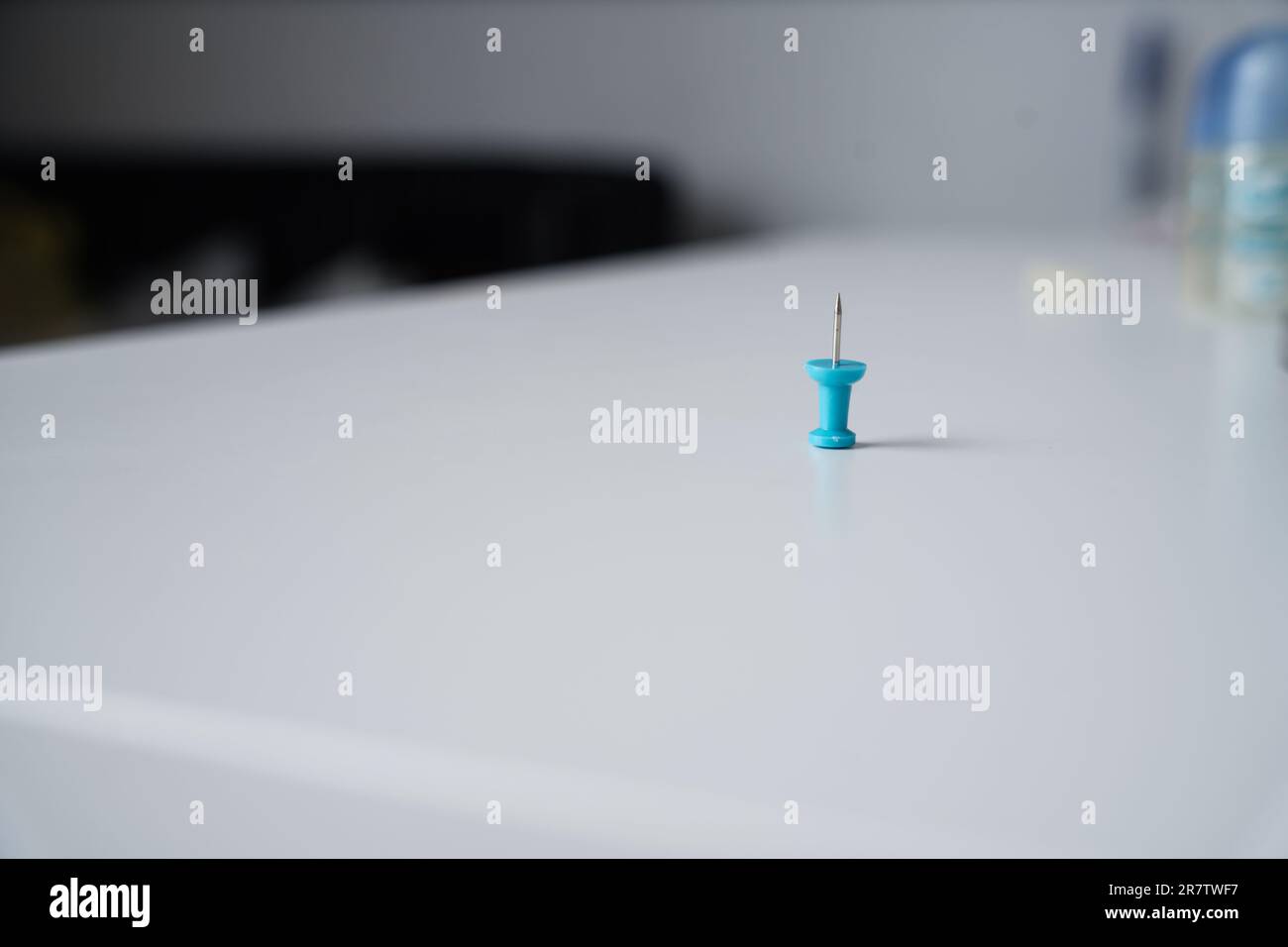 One blue pin stands alone on a white background table with space for ...