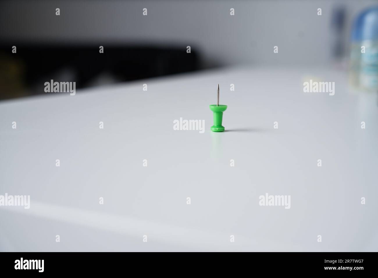 One green pin stands alone on a white background table with space for ...