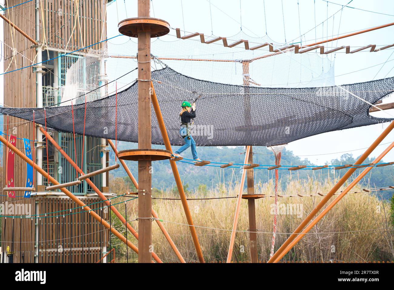 Teenage teen girl in climbing harness equipment, green sports safety ...