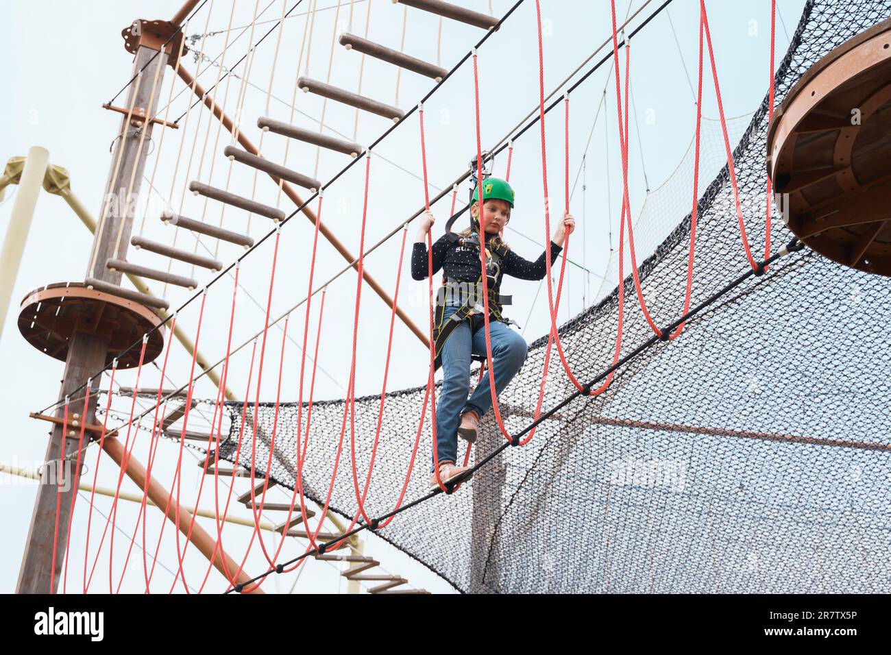 Teenage teen girl in climbing harness equipment, green sports safety ...