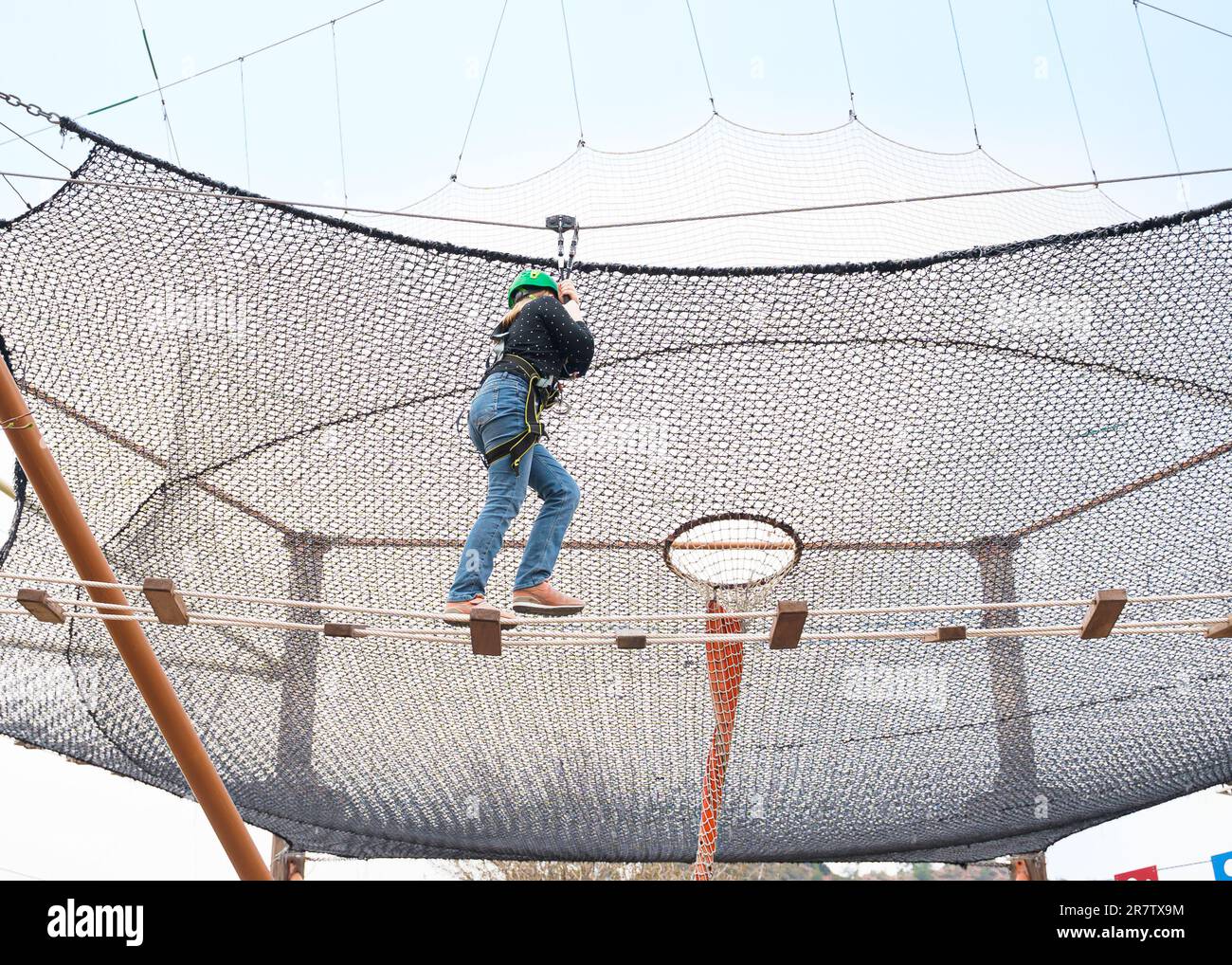 Teenage teen girl in climbing harness equipment, green sports safety ...