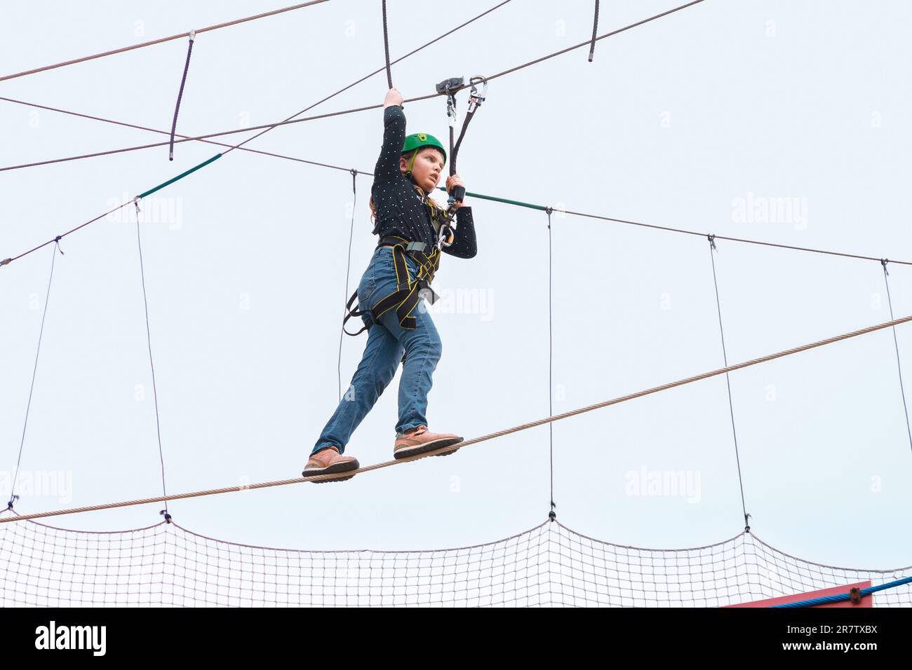 Teenage teen girl in climbing harness equipment, green sports safety ...