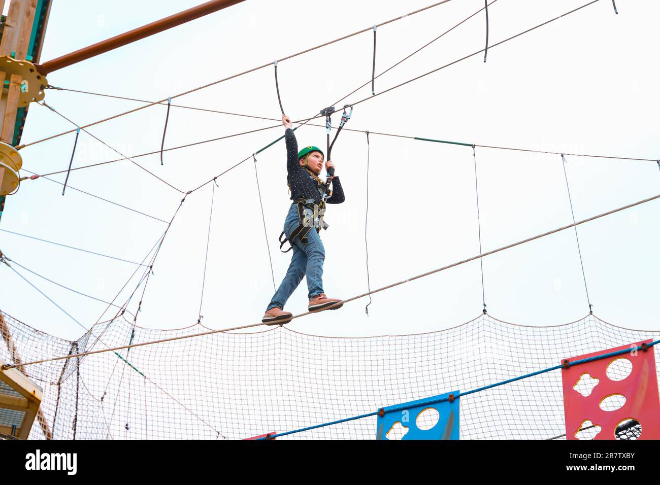 Teenage teen girl in climbing harness equipment, green sports safety ...
