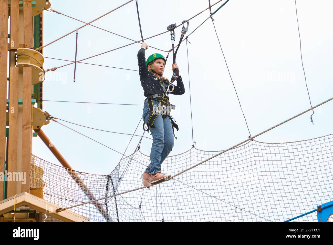 Teenage teen girl in climbing harness equipment, green sports safety ...