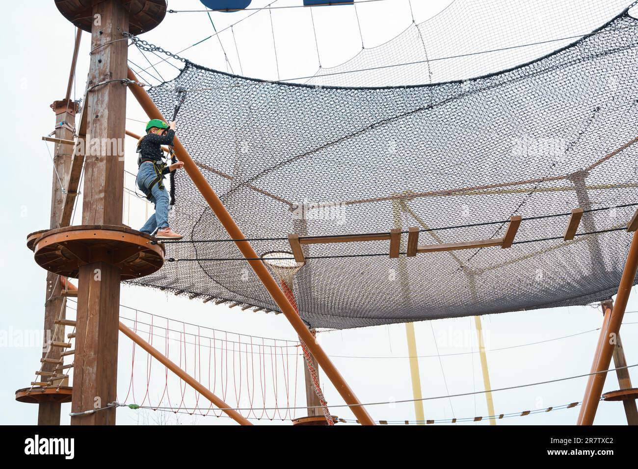 Teenage teen girl in climbing harness equipment, green sports safety ...