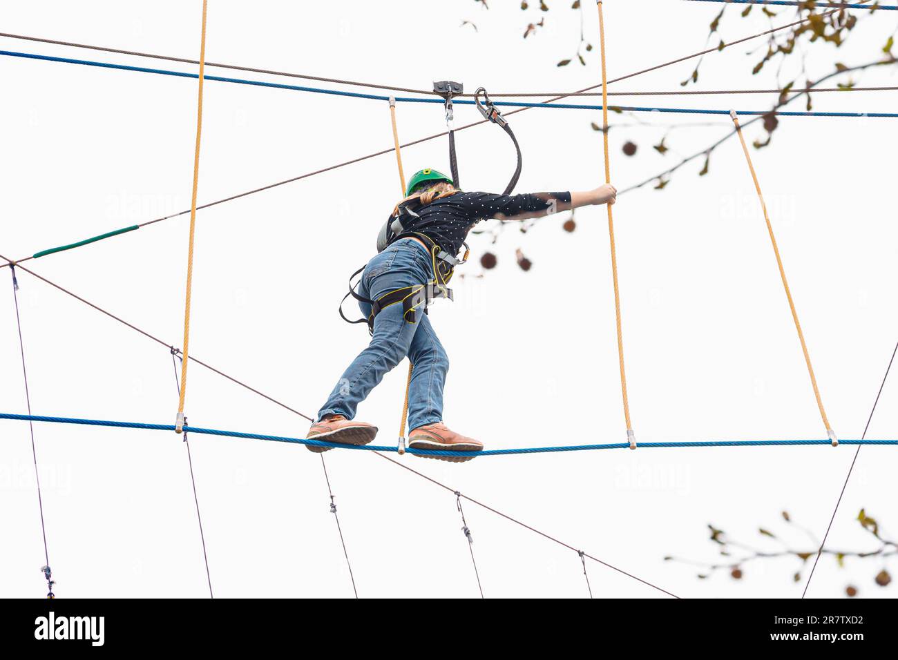 Teenage teen girl in climbing harness equipment, green sports safety ...
