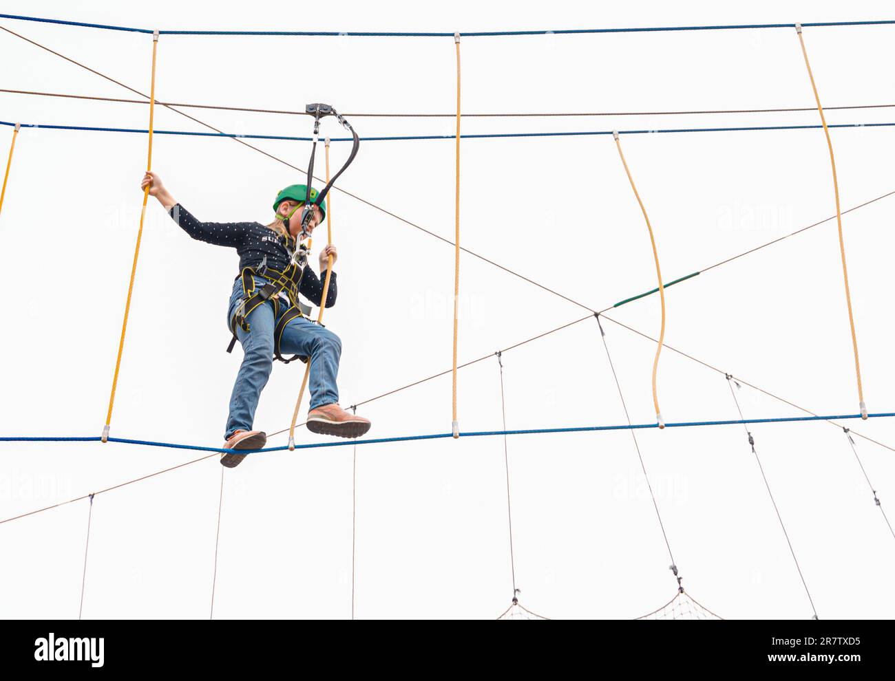 Teenage teen girl in climbing harness equipment, green sports safety ...
