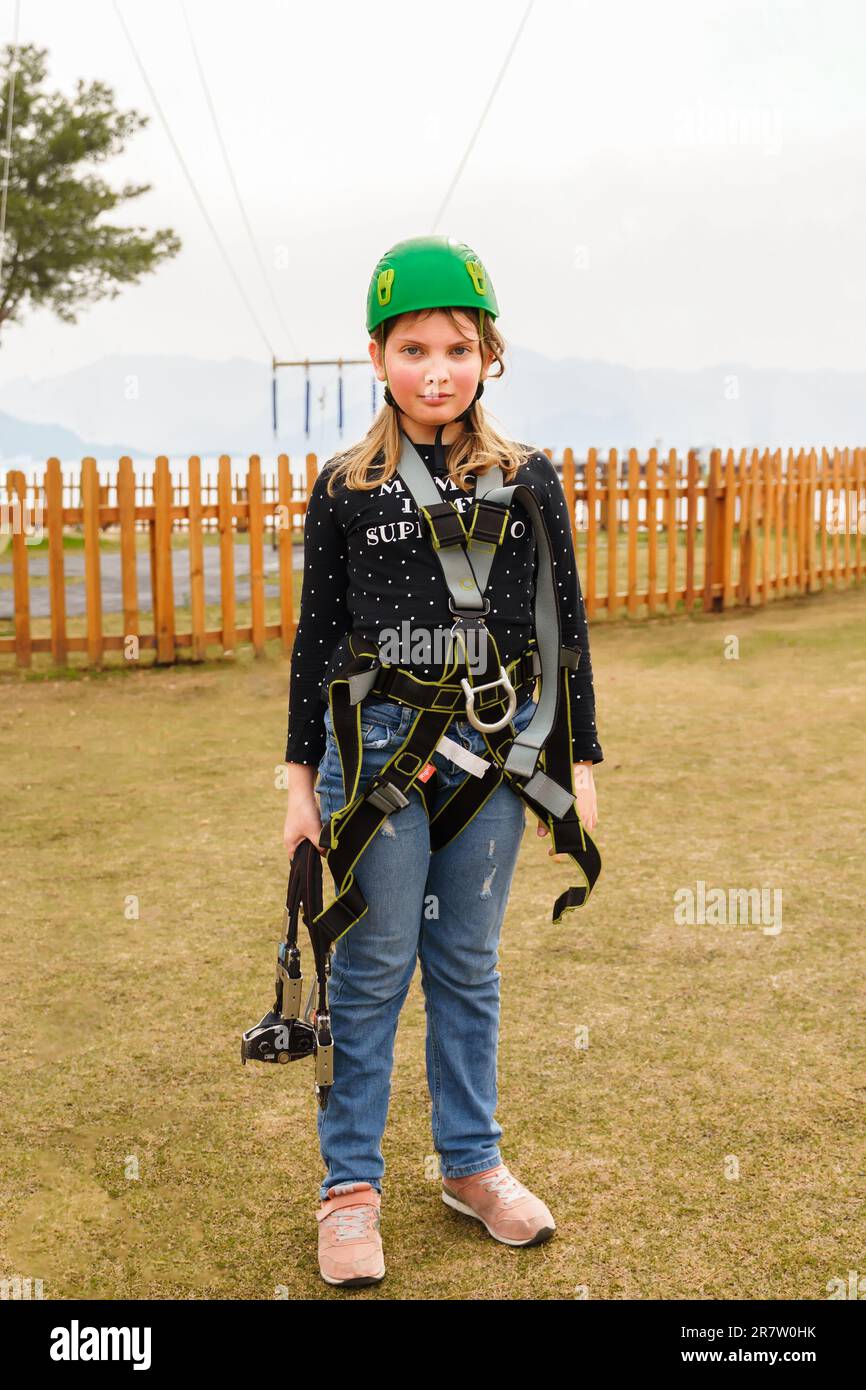 Teenage teen girl in climbing harness equipment, green sports safety ...