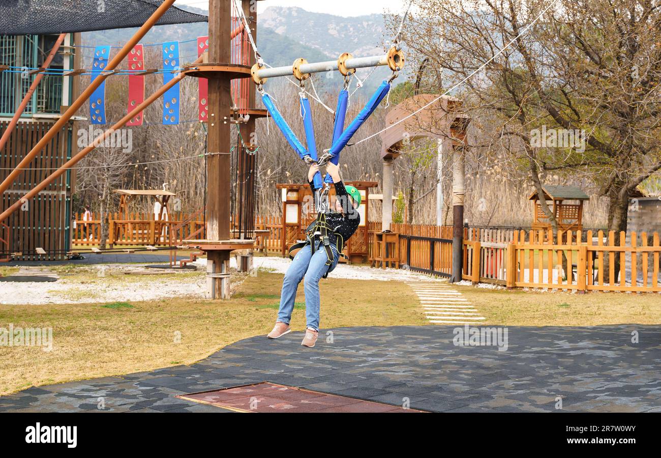 Teenage teen girl in climbing harness equipment, green sports safety ...