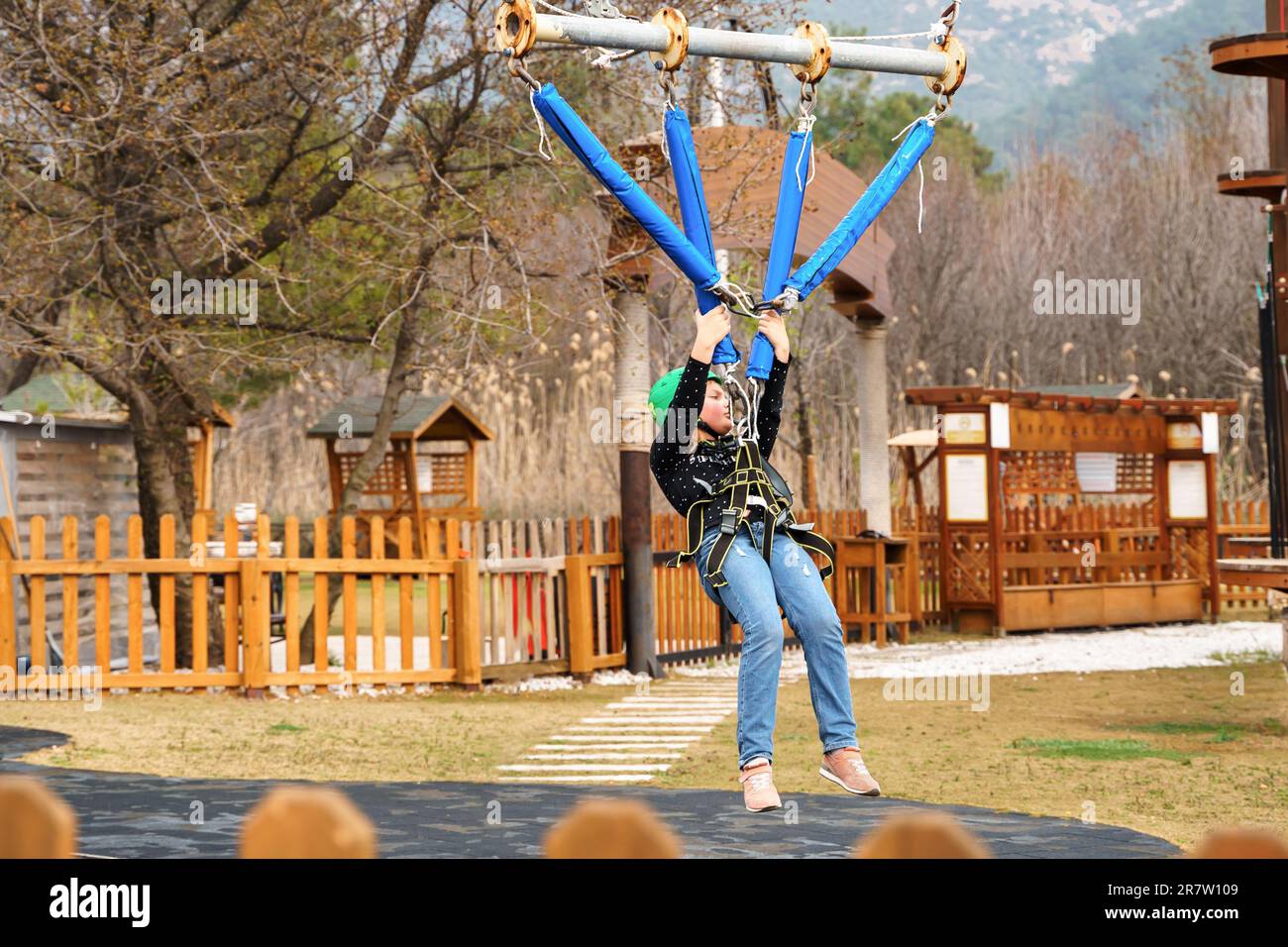 Teenage teen girl in climbing harness equipment, green sports safety ...