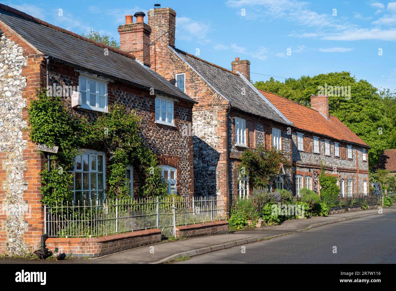 Row of traditional pretty brick and flint cottages in street in quaint ...