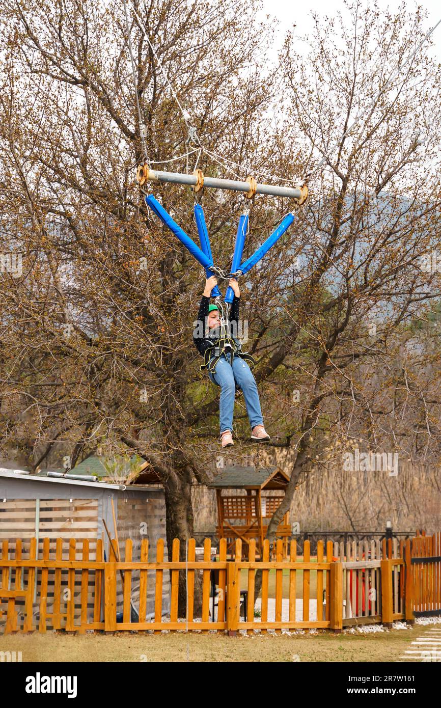 Teenage teen girl in climbing harness equipment, green sports safety ...