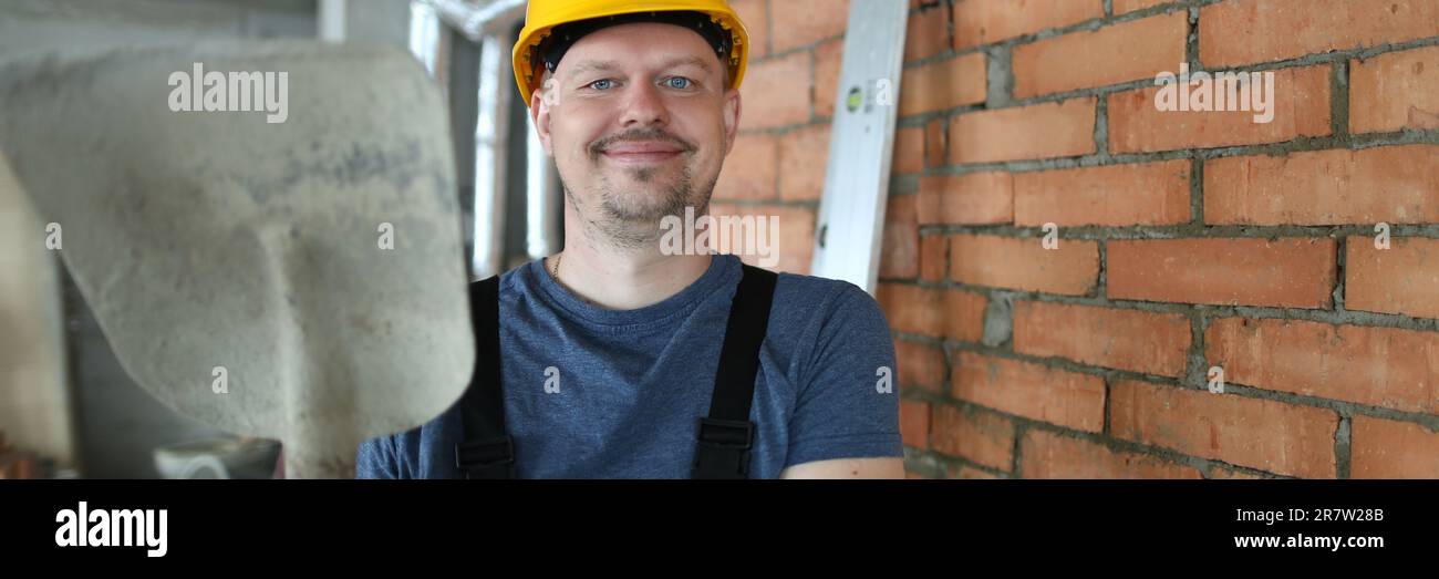 Worker in hard hat holds cement shovel Stock Photo - Alamy