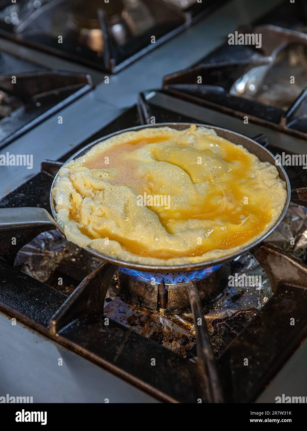 The chef is cooking and stirring the omelette. Unrecognizable hands ...