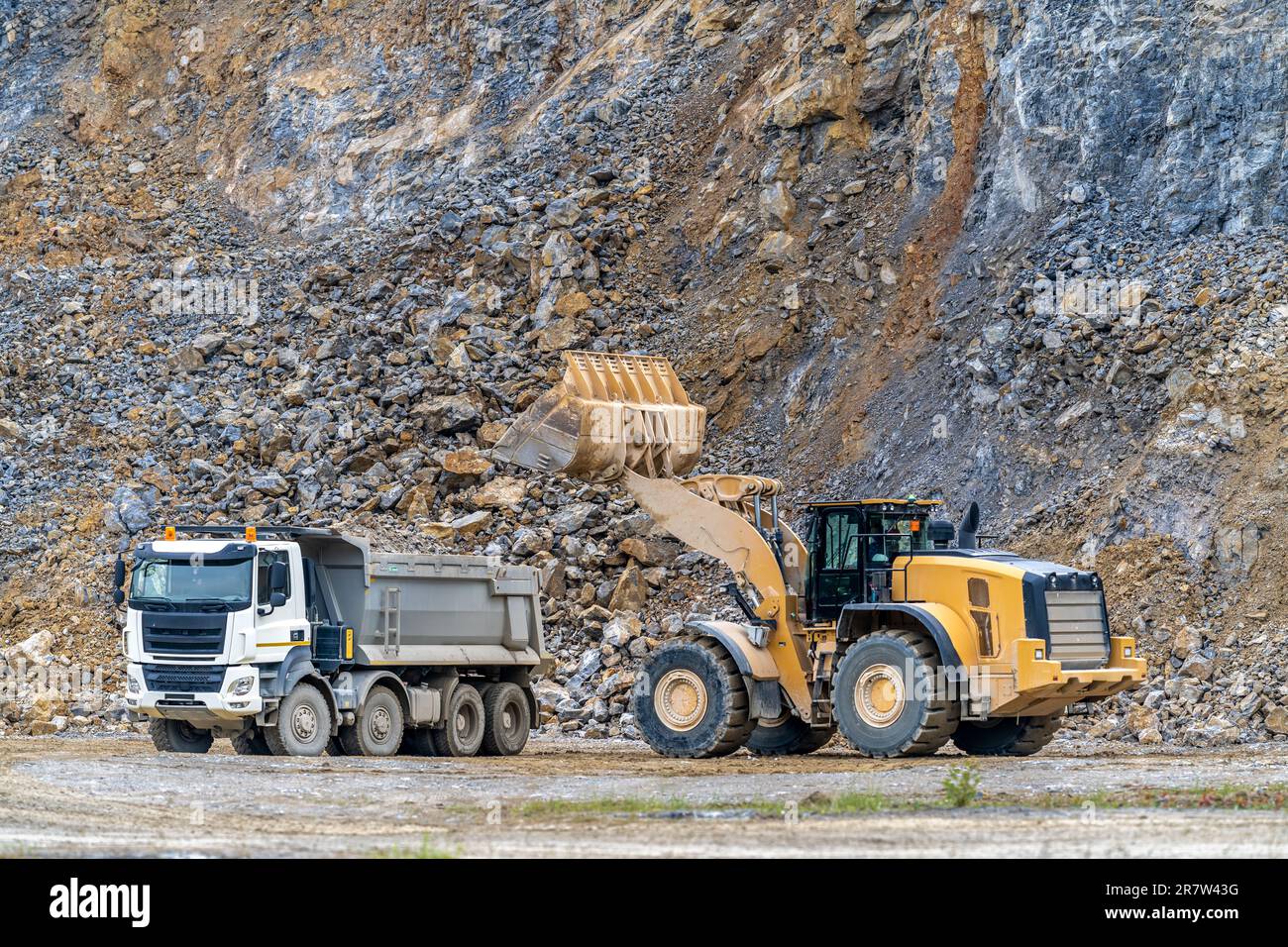 an excavator is loading a truck with stone at a quarry Stock Photo - Alamy