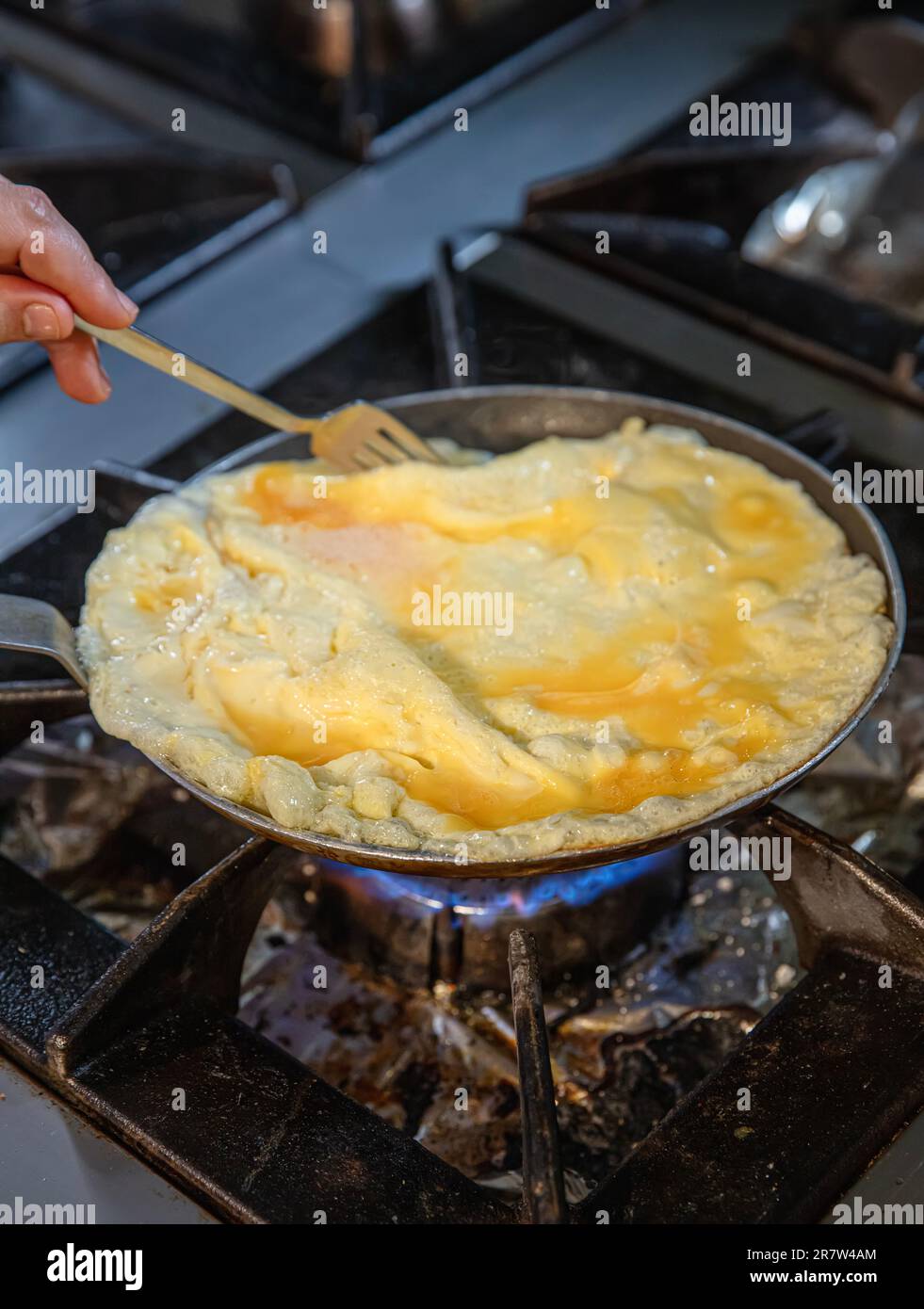 The chef is cooking and stirring the omelette. Unrecognizable hands ...
