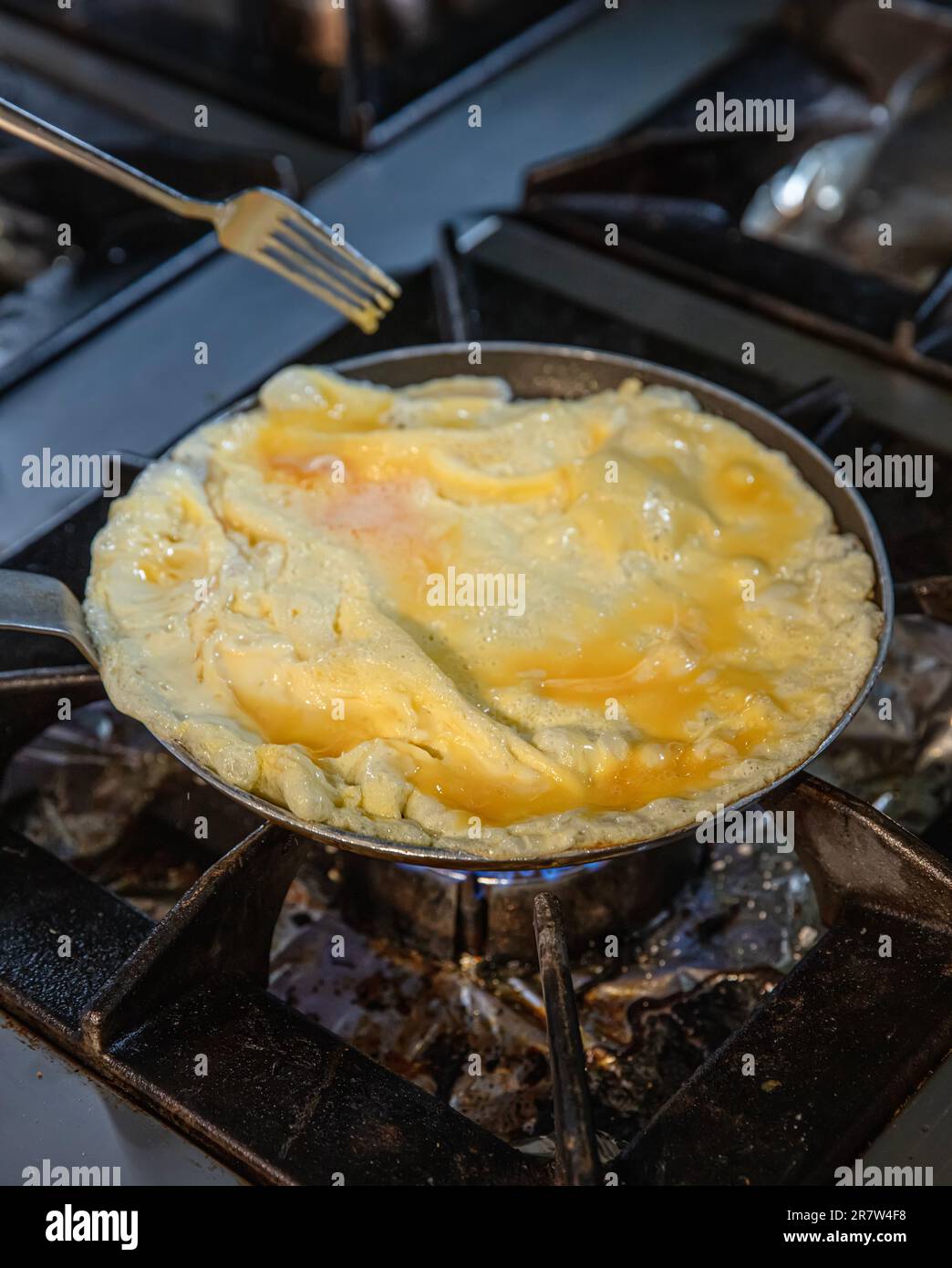 The chef is cooking and stirring the omelette. Unrecognizable hands ...