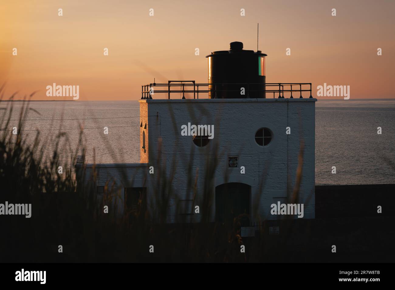 The Bamburgh Lighthouse with its smiley face at sunset with Lindisfarne ...