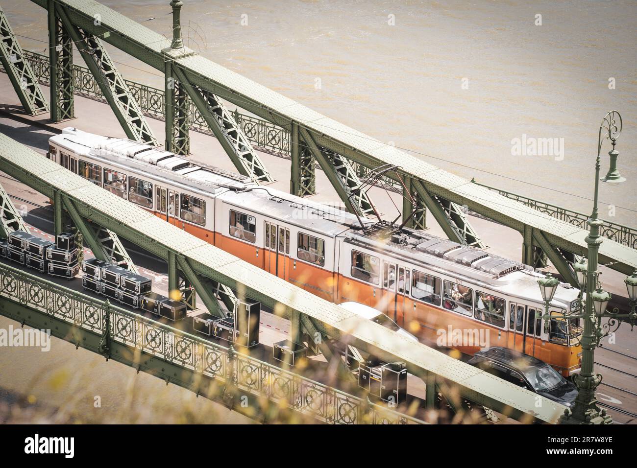 The old yellow tram crossing the green bridge over the Danube river in ...