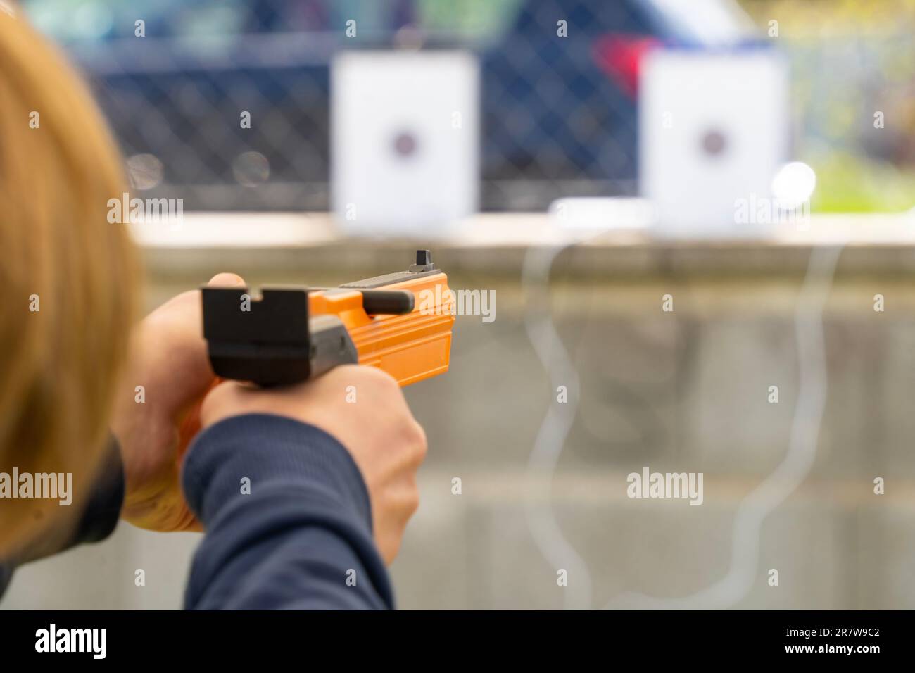 Hand-held orange laser sports pistol while aiming Stock Photo - Alamy