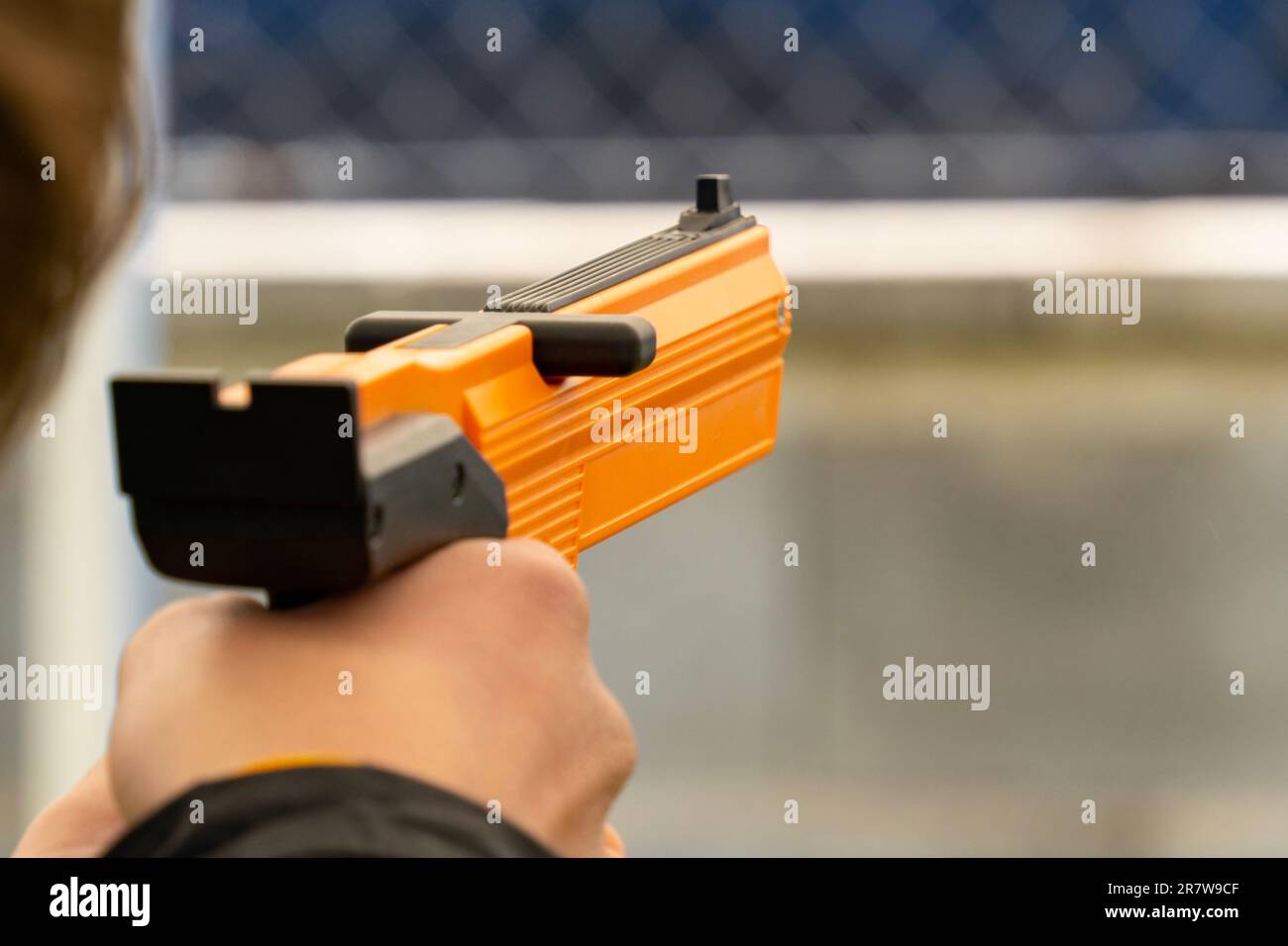 Hand-held orange laser sports pistol while aiming Stock Photo - Alamy