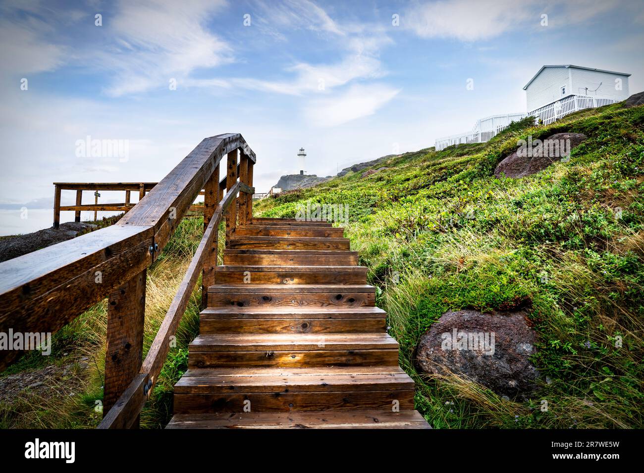 Wooden staircase with handrail leading up to a tall white lighthouse ...