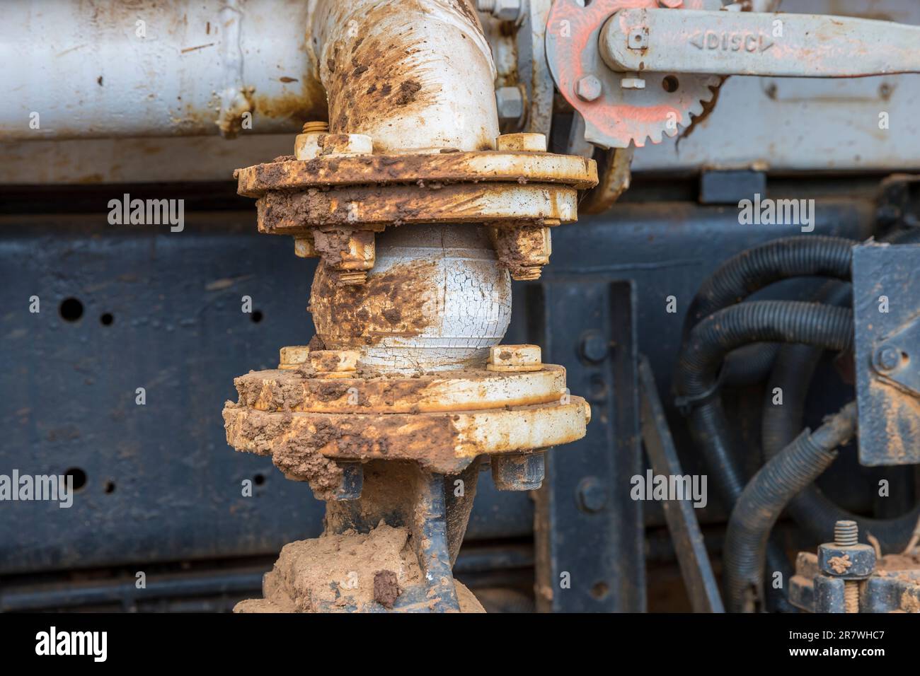 Photograph of a large valve and fittings covered in mud on a large ...