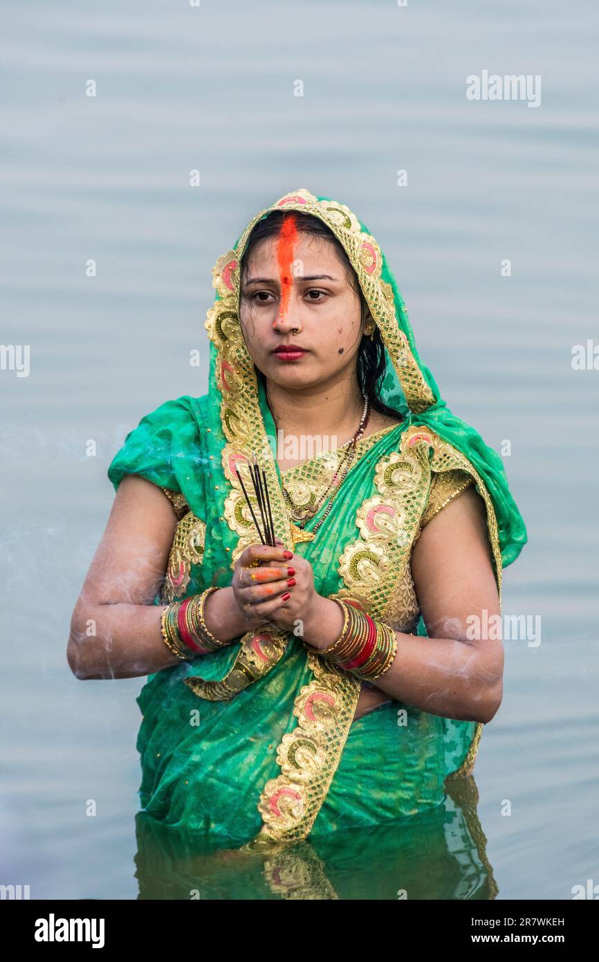 A devotee makes an offering and prays in the Ganges during Chhath Puja ...