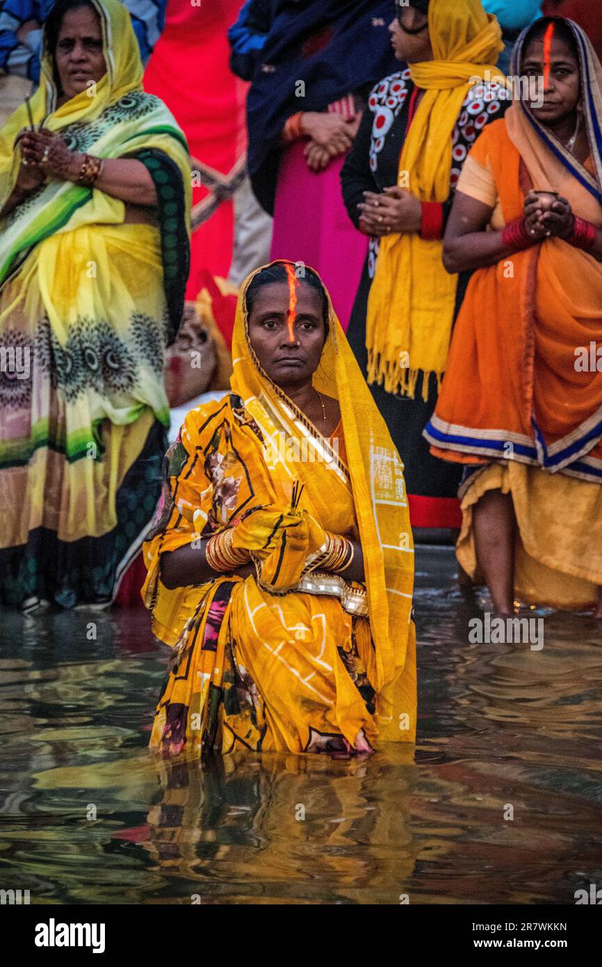 A devotee makes an offering and prays in the Ganges during Chhath Puja ...
