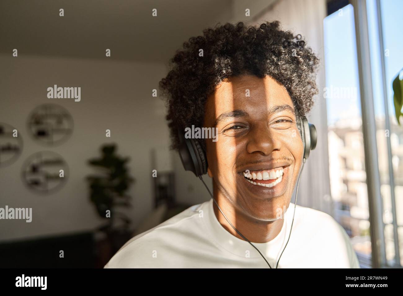 Happy gen z African American guy wearing headphones listening music at ...