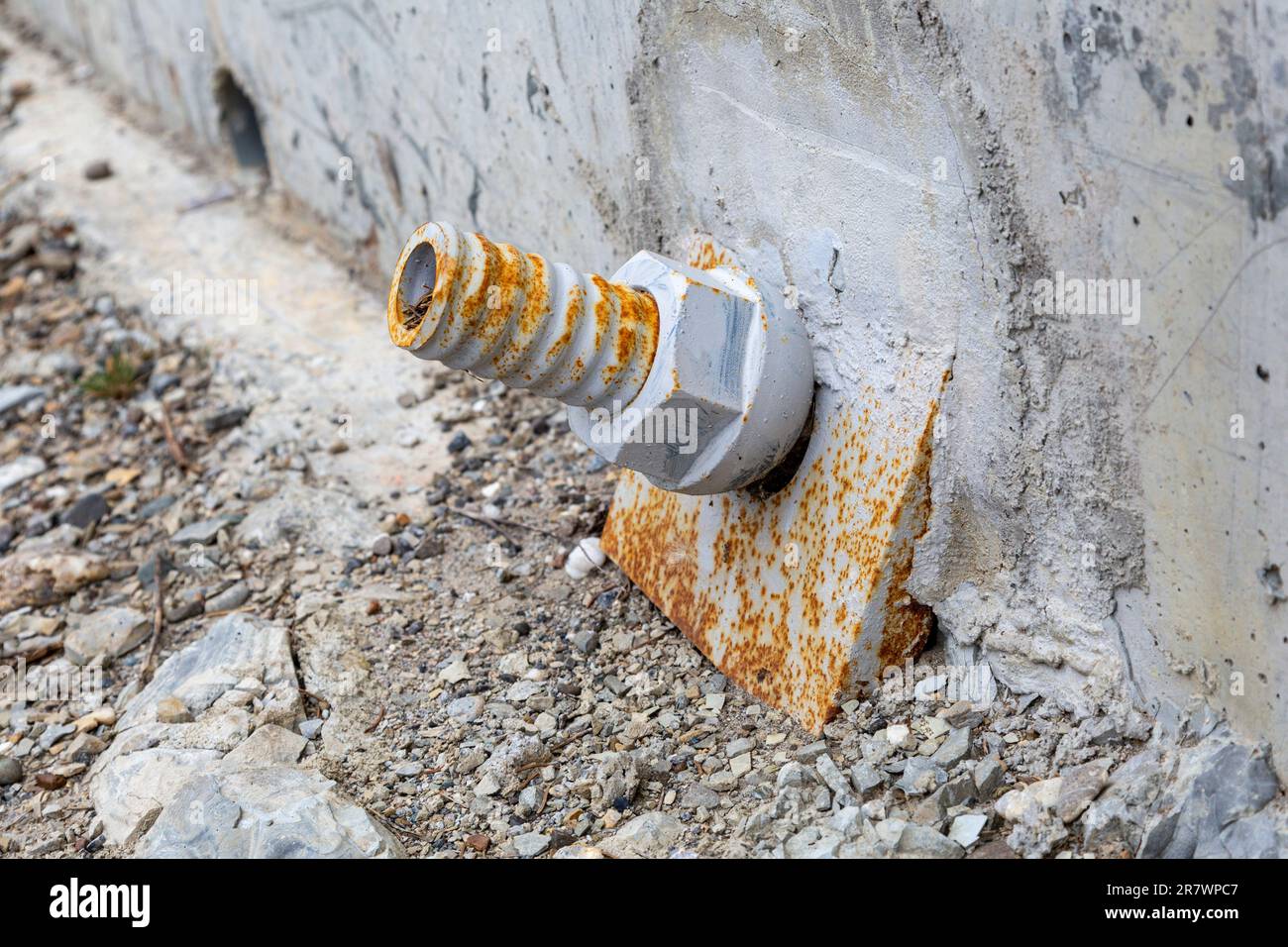 twisted metal nut covered with rust on the concrete wall of the bridge ...