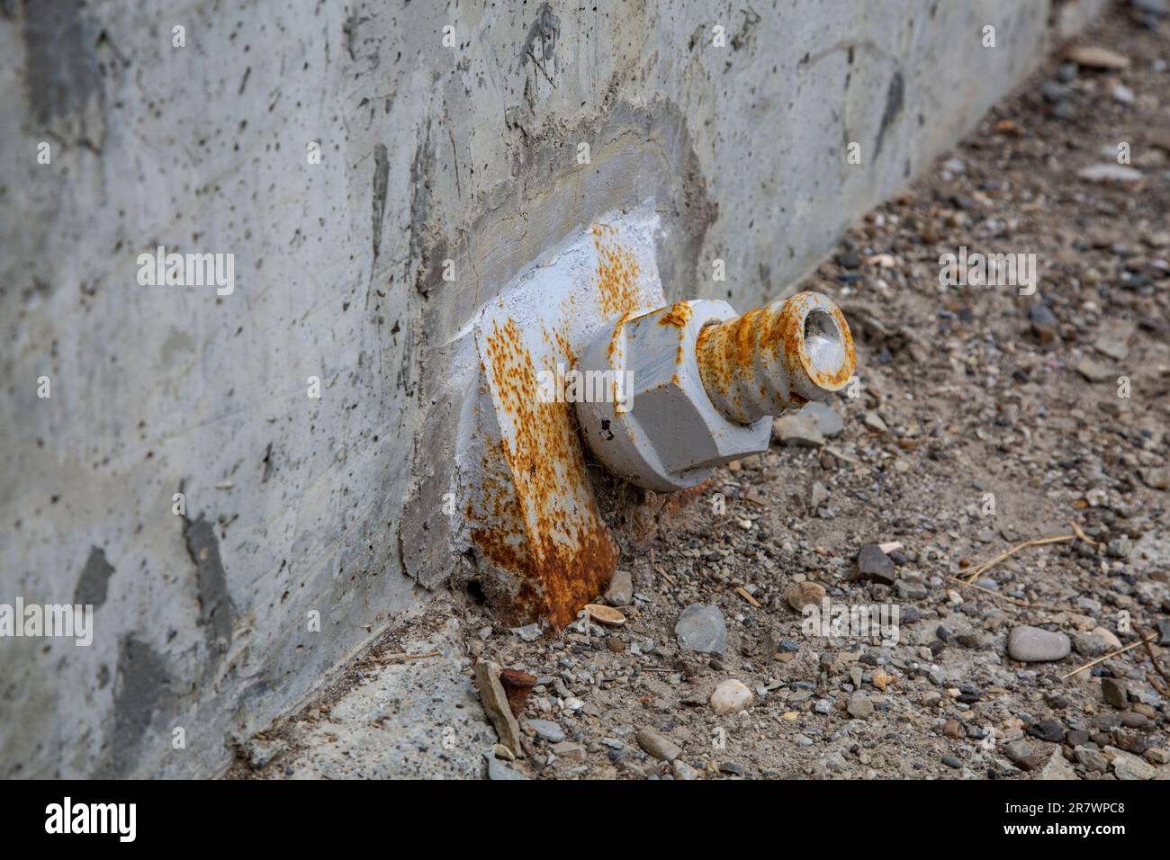 twisted metal nut covered with rust on the concrete wall of the bridge ...